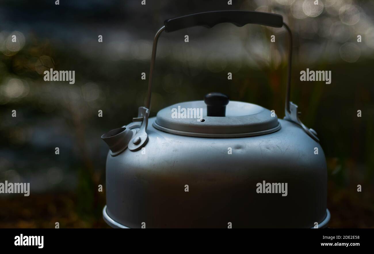 A simple steel kettle boiling water by the waters edge on a hike Stock ...