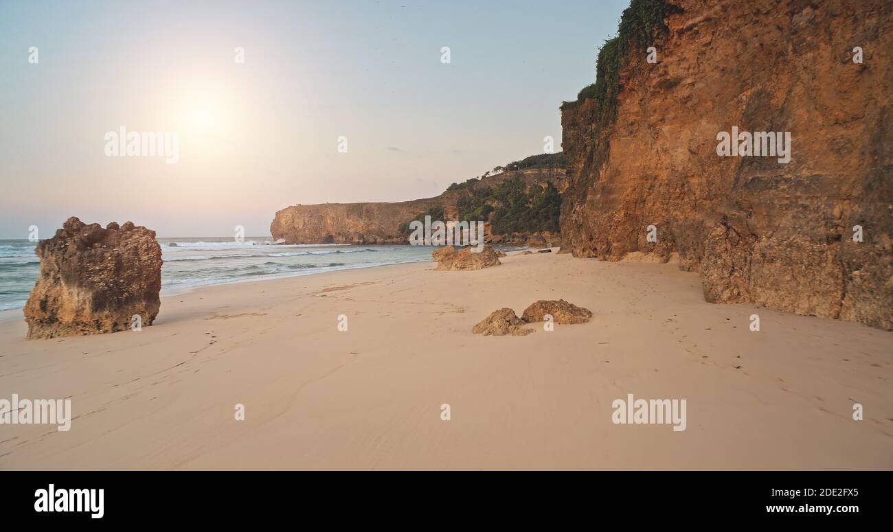 Sun light above sand beach at clean ocean bay water aerial. Cliff shore ...