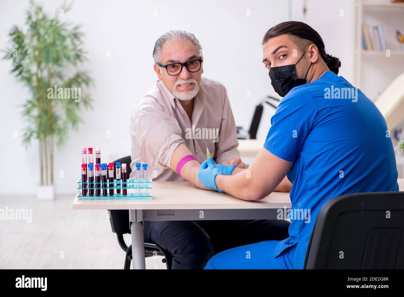 Old patient visiting young male doctor in blood transfusion concept ...