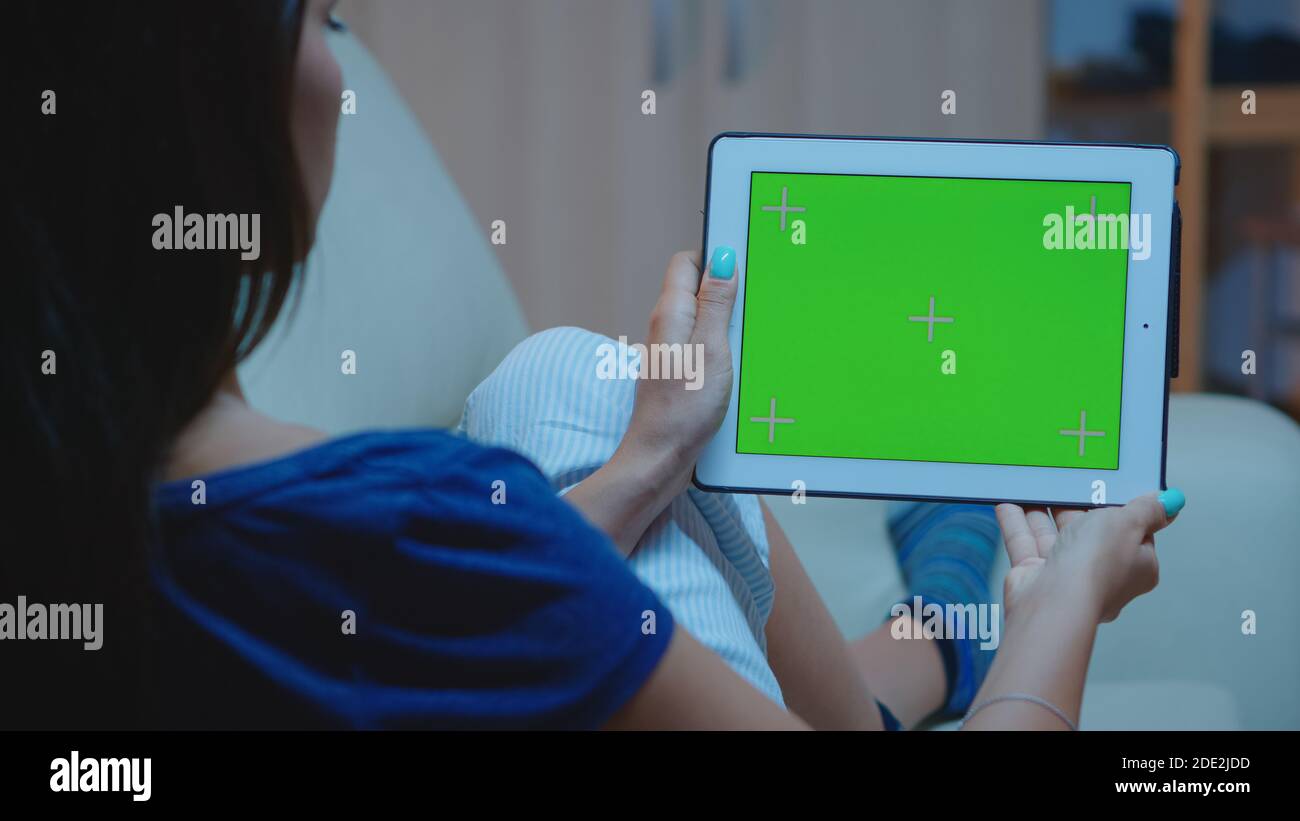 Woman reading on digital tablet with green screen background while ...