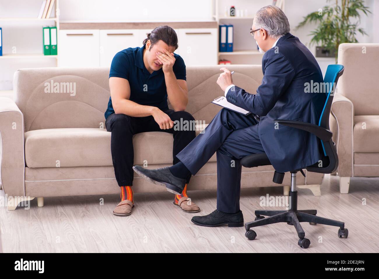 Young man visiting old psychologist Stock Photo - Alamy