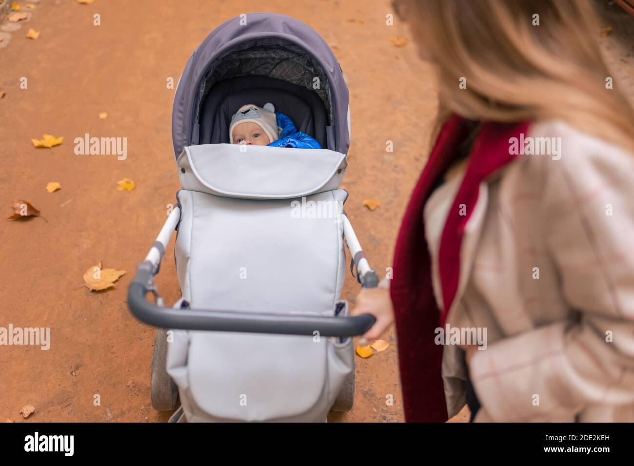Back view of mother rocking stroller with a little baby Stock Photo - Alamy