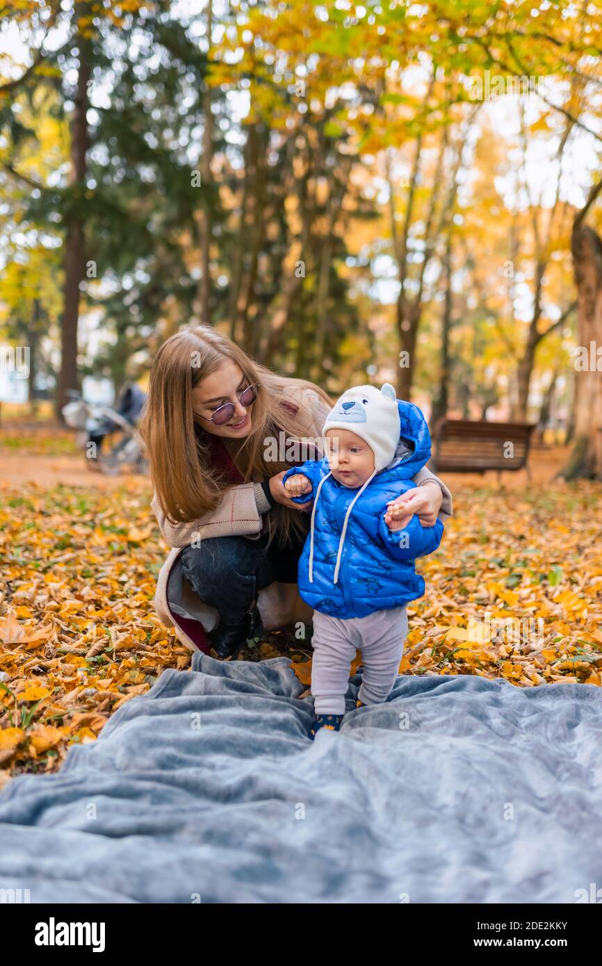 Mom teaches the kid to walk. Infant with the help of his mother takes ...