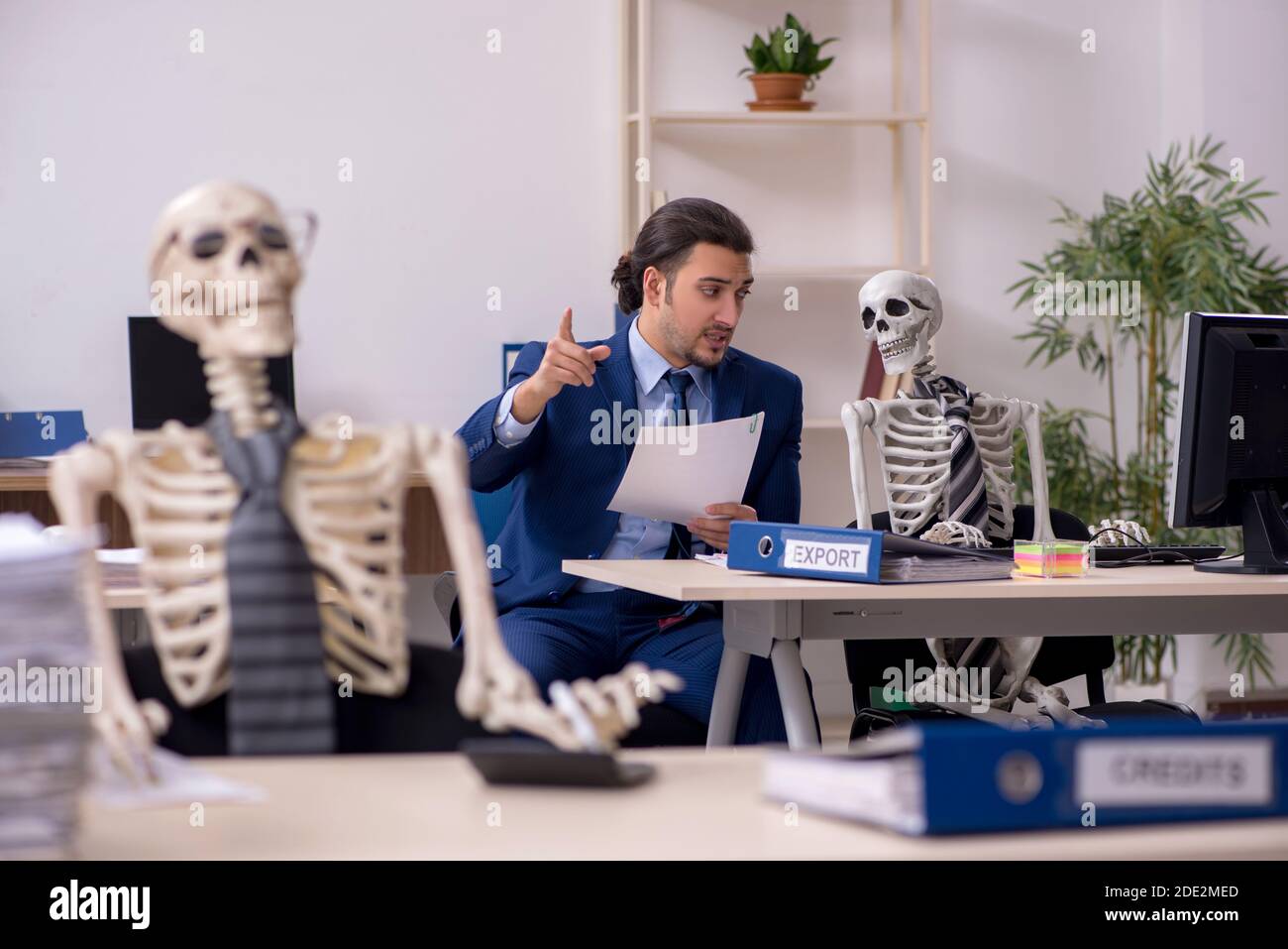 Young employee with skeletons in the office Stock Photo - Alamy