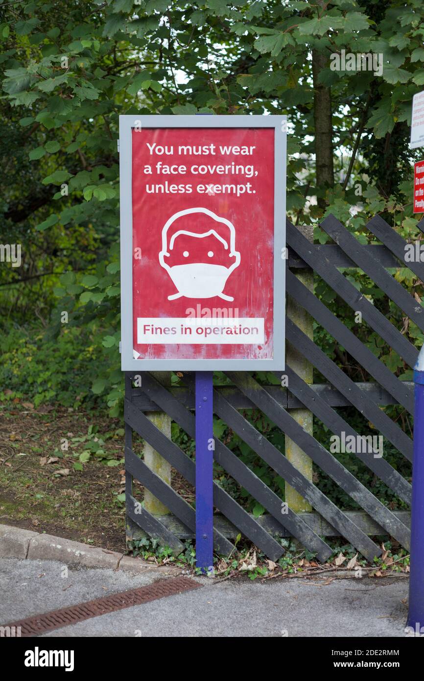 Sign at a UK railway station telling rail passengers to wear a face ...
