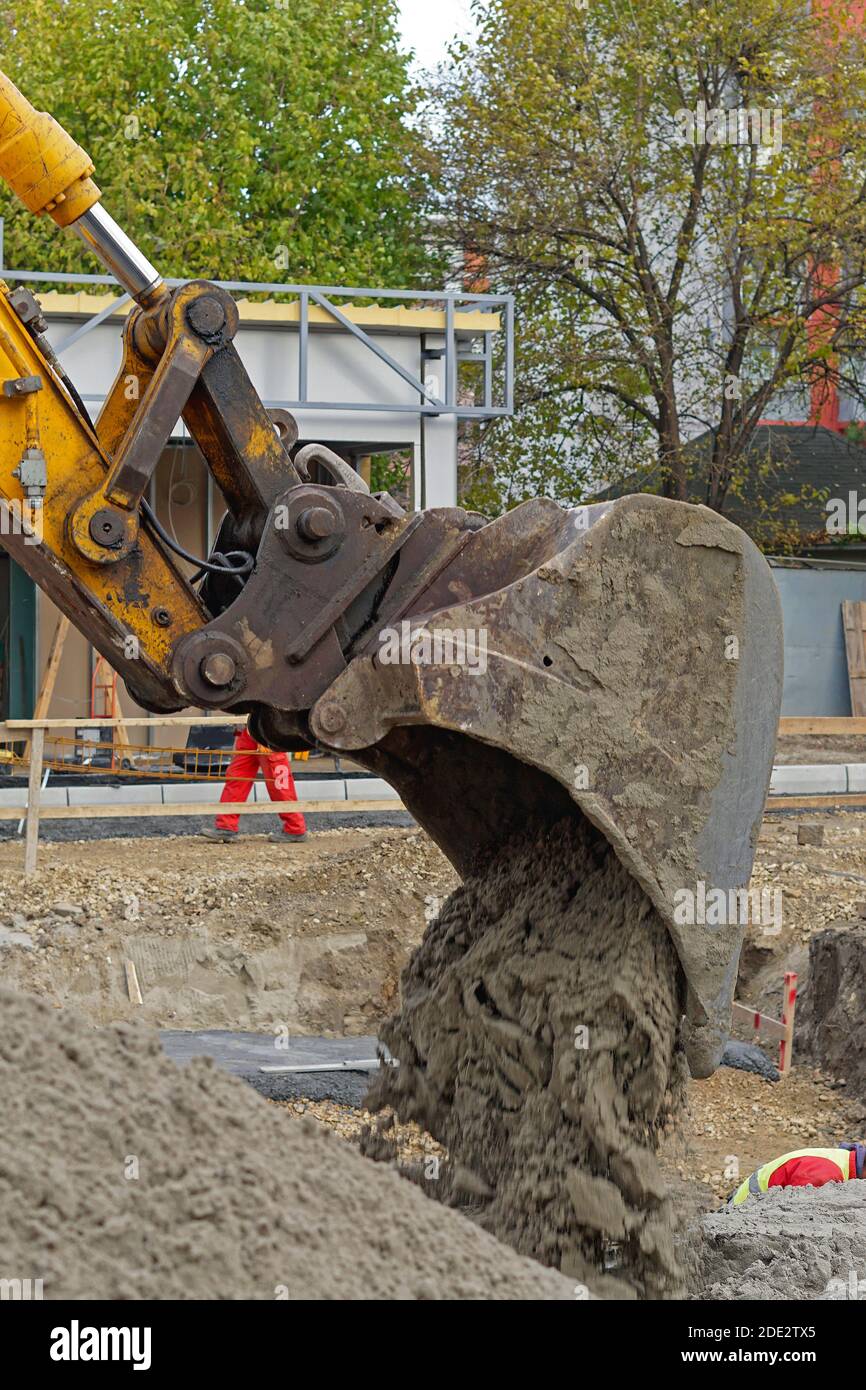 Backhoe digger unloading sand at construction site Stock Photo - Alamy