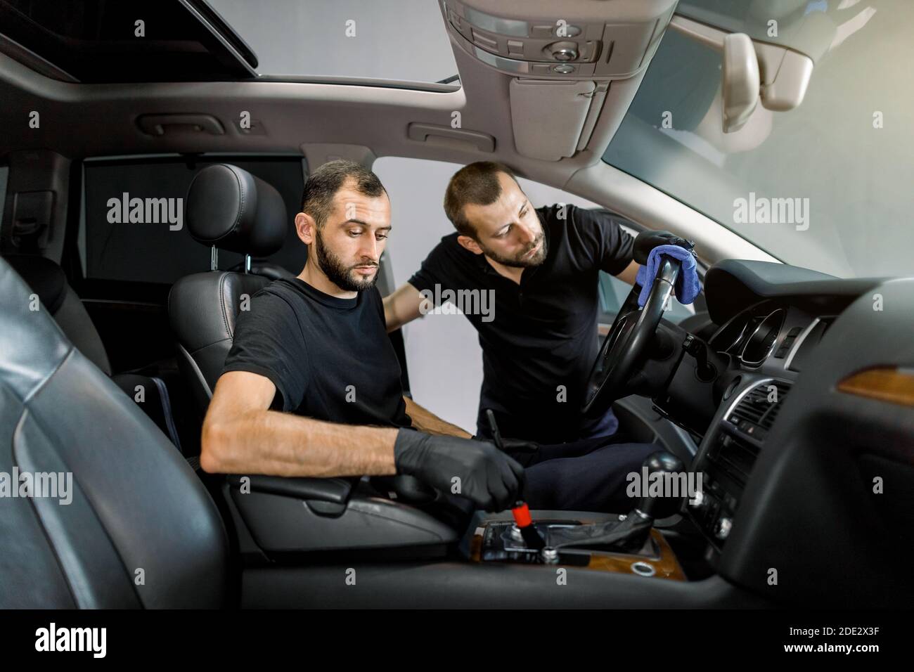 Car detailing and maintenance concept. Two male workers in black ...