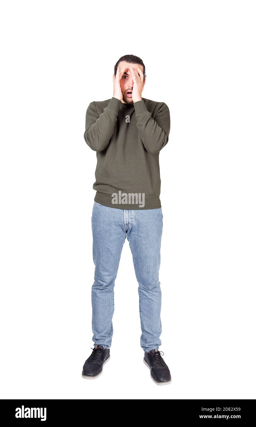 Full length portrait of scared young man looking through fingers as ...