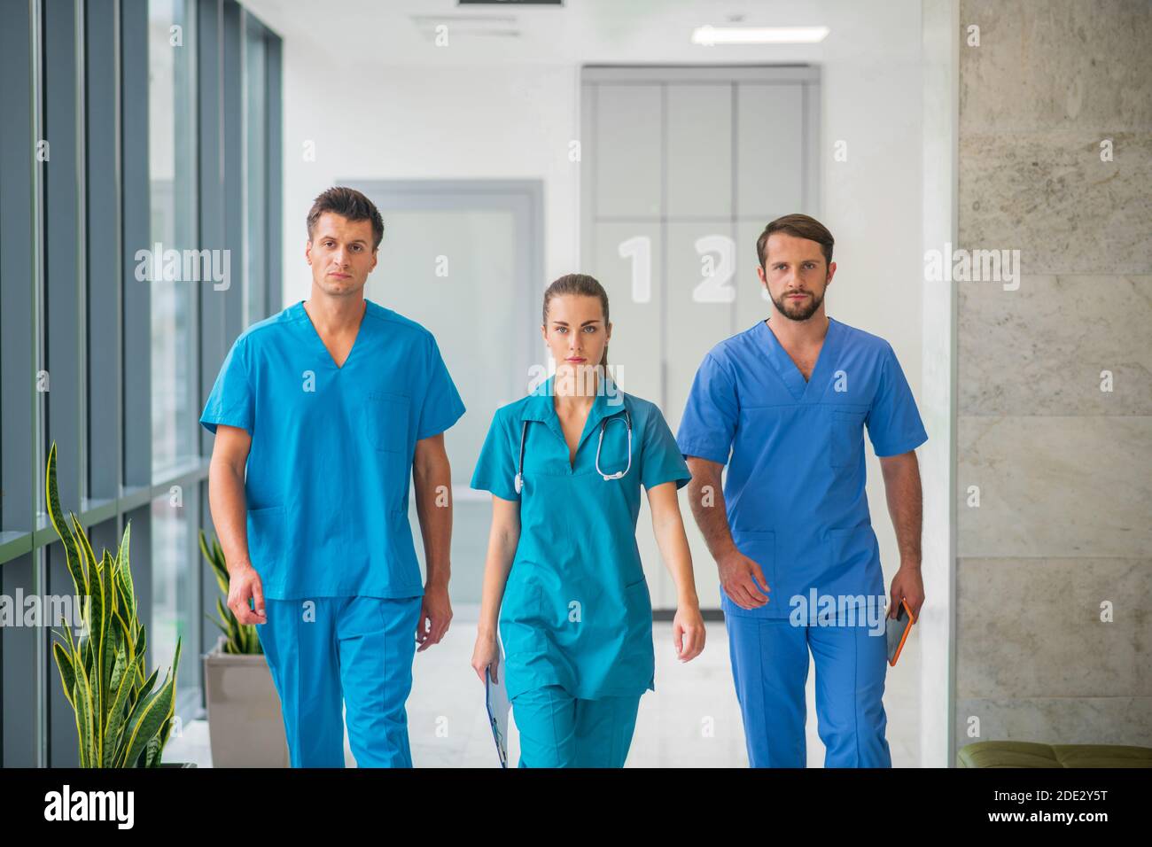 Three doctors walking together in the hospital corridor Stock Photo - Alamy