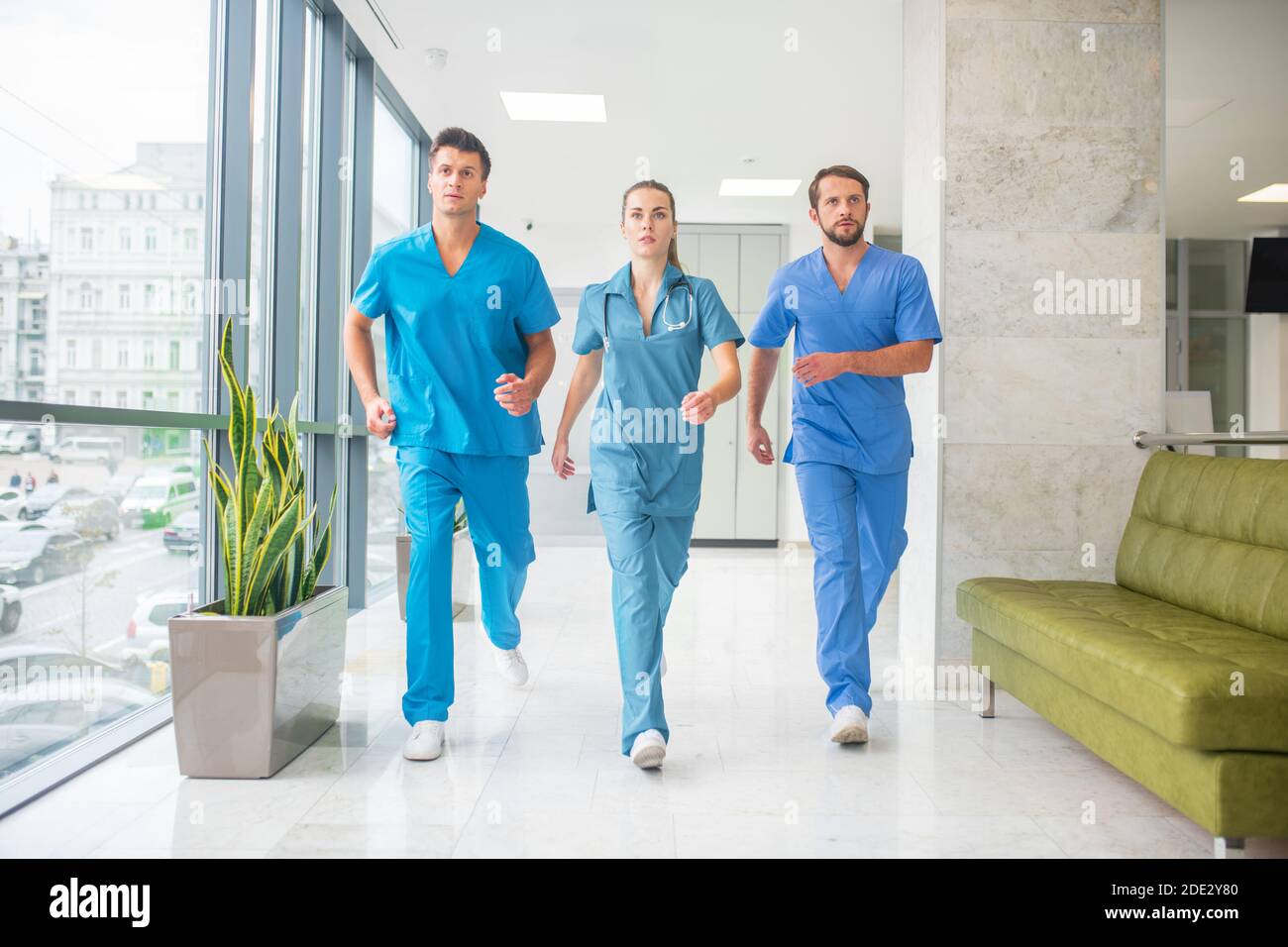 Three doctors running throtugh the hospital corridor being in a hurry ...