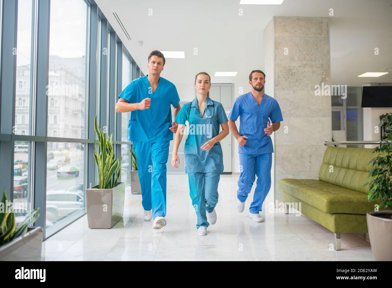 Three doctors running through the hospital corridor being in a hurry ...