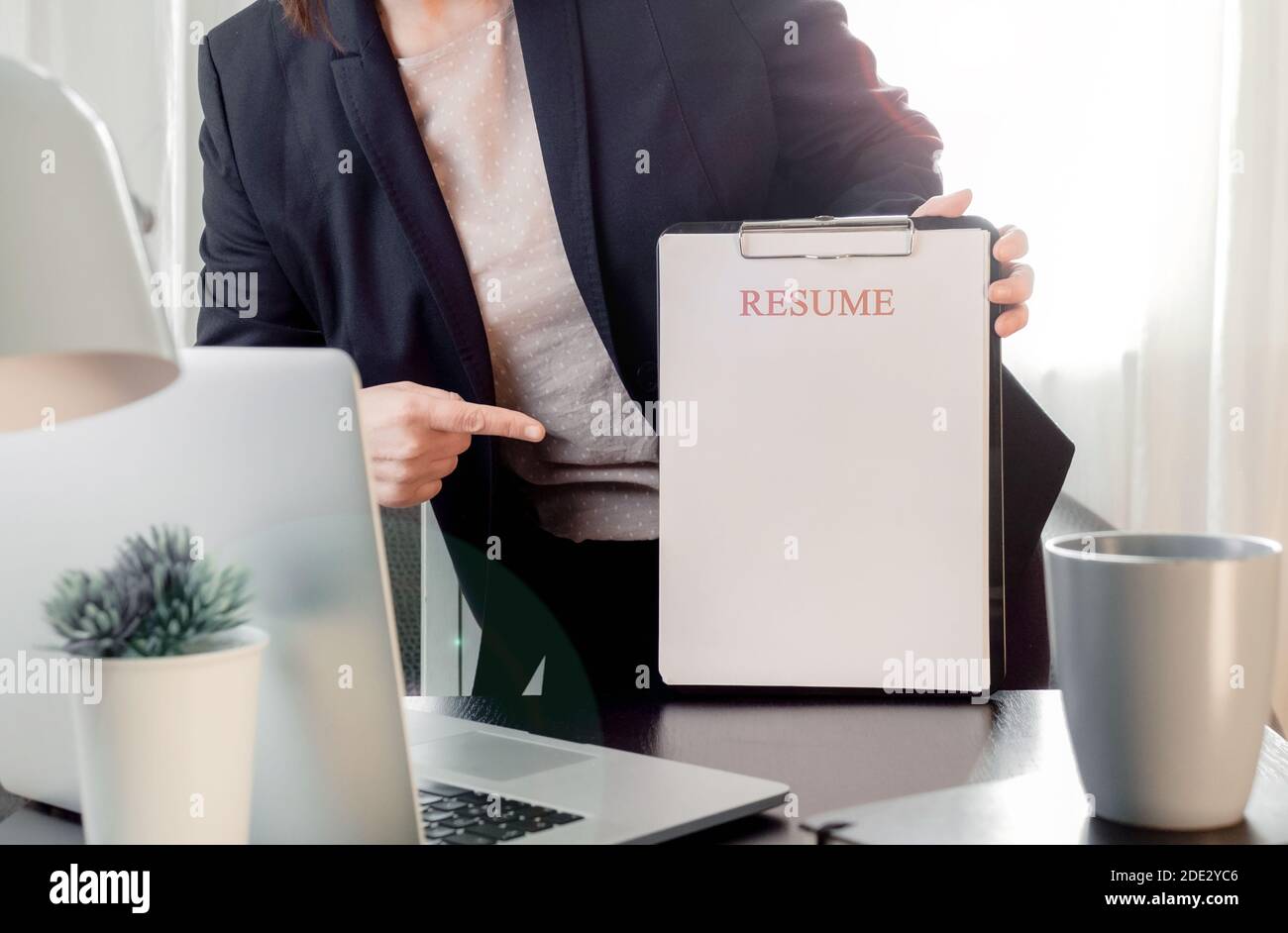 Woman hands holding resume application near her workplace with laptop ...