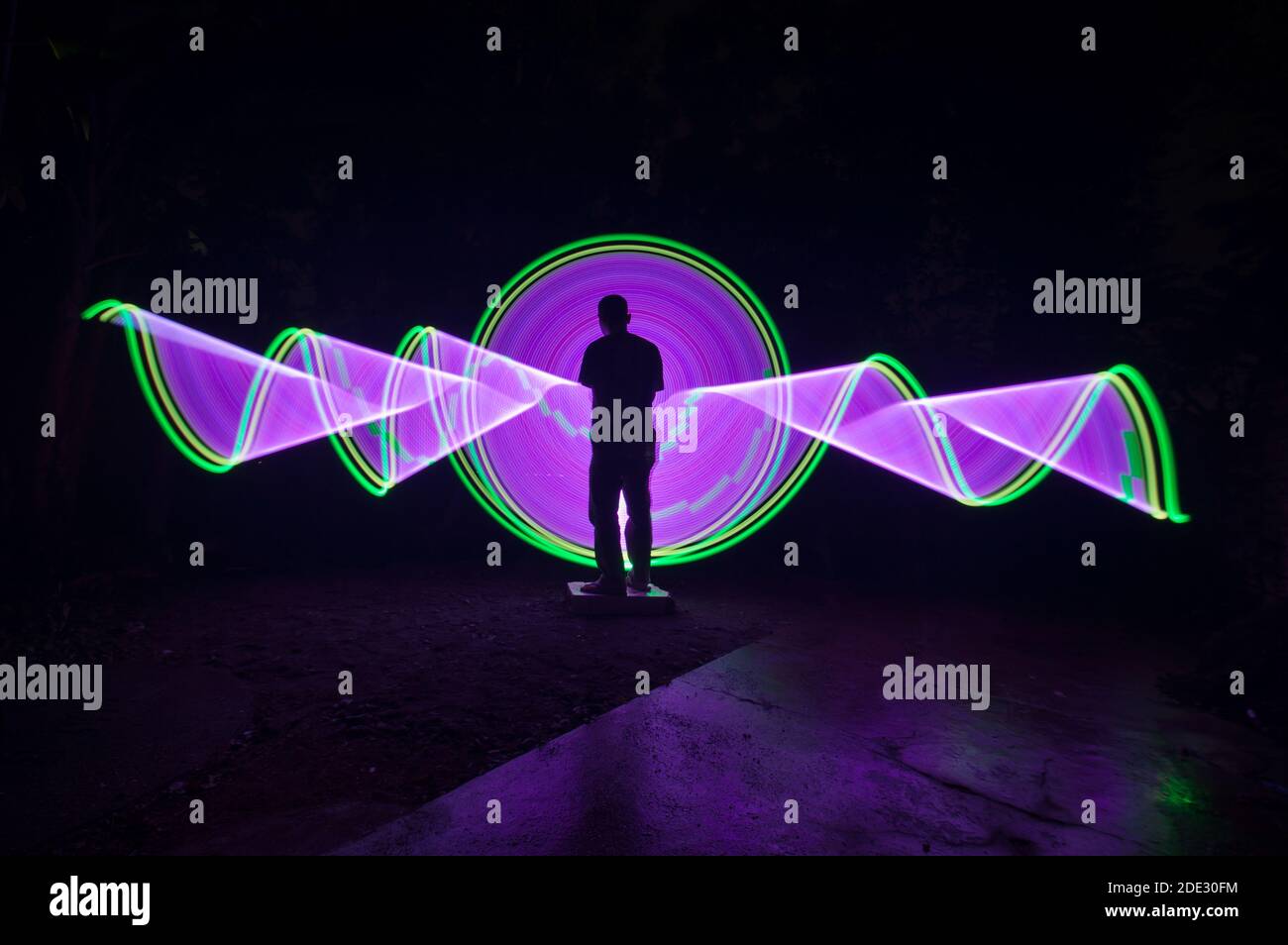 One person standing alone against beautiful Colourful LED light ...