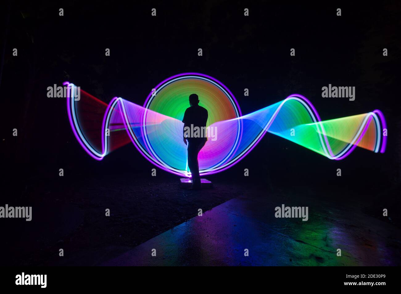 One person standing alone against beautiful Colourful LED light ...
