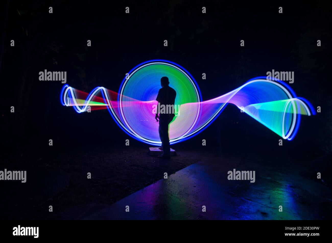 One person standing alone against beautiful Colourful LED light ...