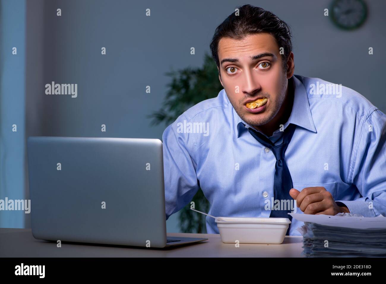 Hungry employee working late in office Stock Photo - Alamy