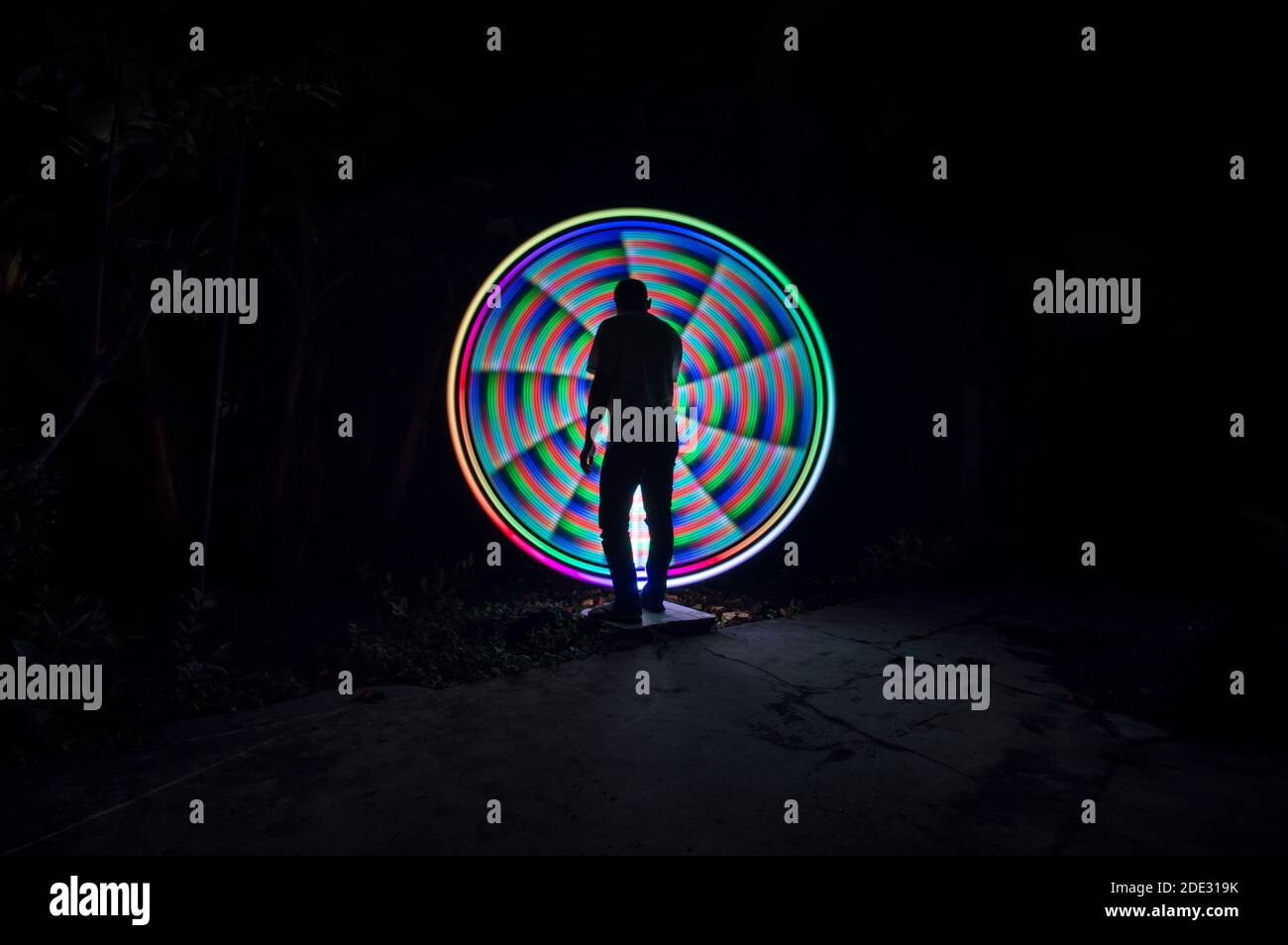 One person standing alone against beautiful Colourful LED light ...