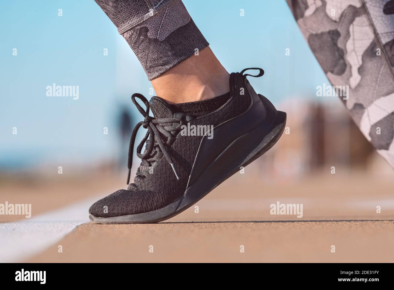 Running shoe of female athlete on the starting line of a stadium track ...