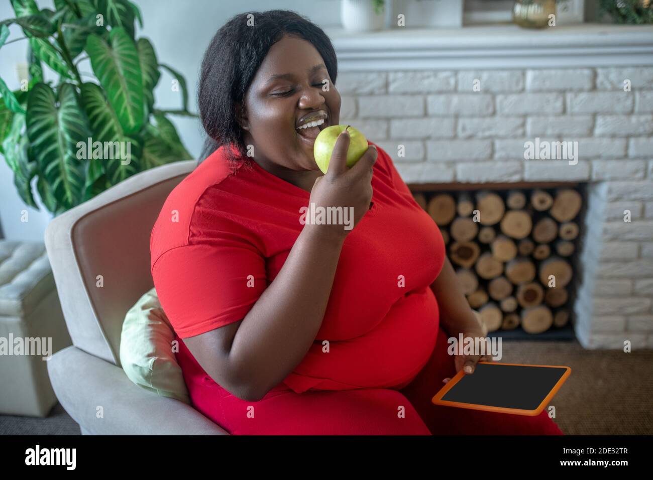 Plus size african american woman eating an apple Stock Photo - Alamy