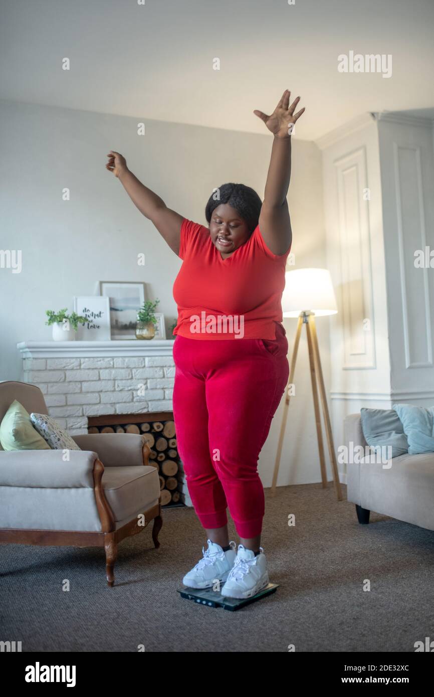 Plus Size African American Woman Checking Her Weight And Looking Happy