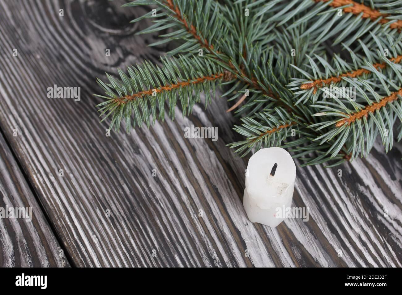 Candle stub and fir branches. On black pine boards Stock Photo - Alamy