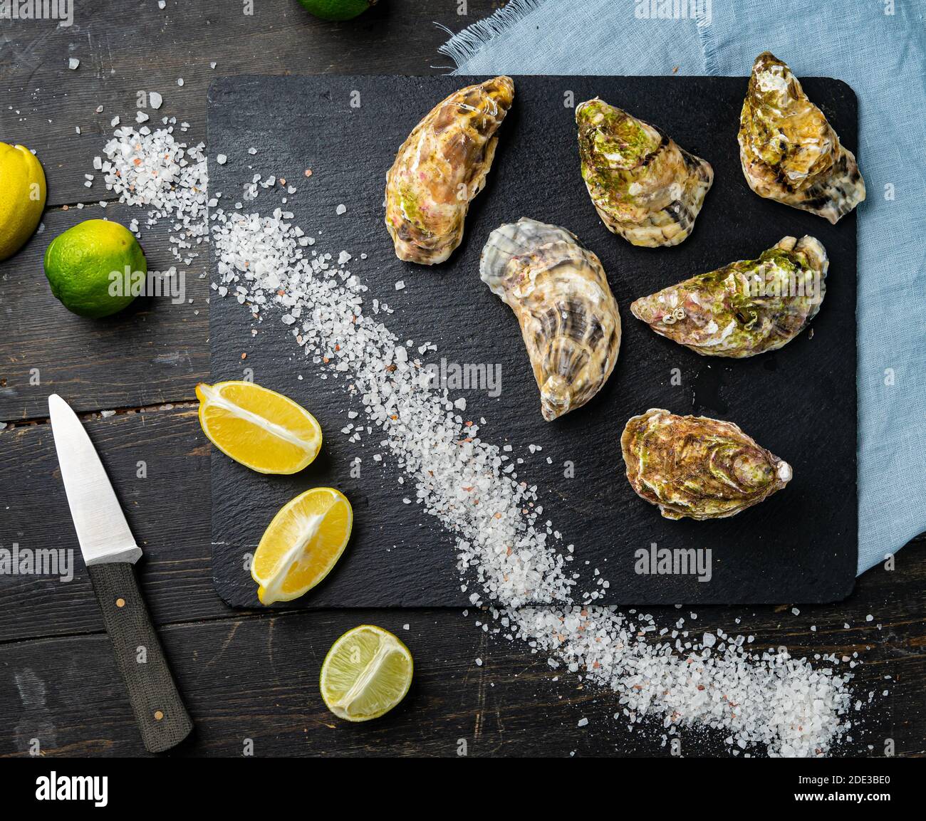 Fresh oysters on a black stone background. Top view. Oyster dinner in ...