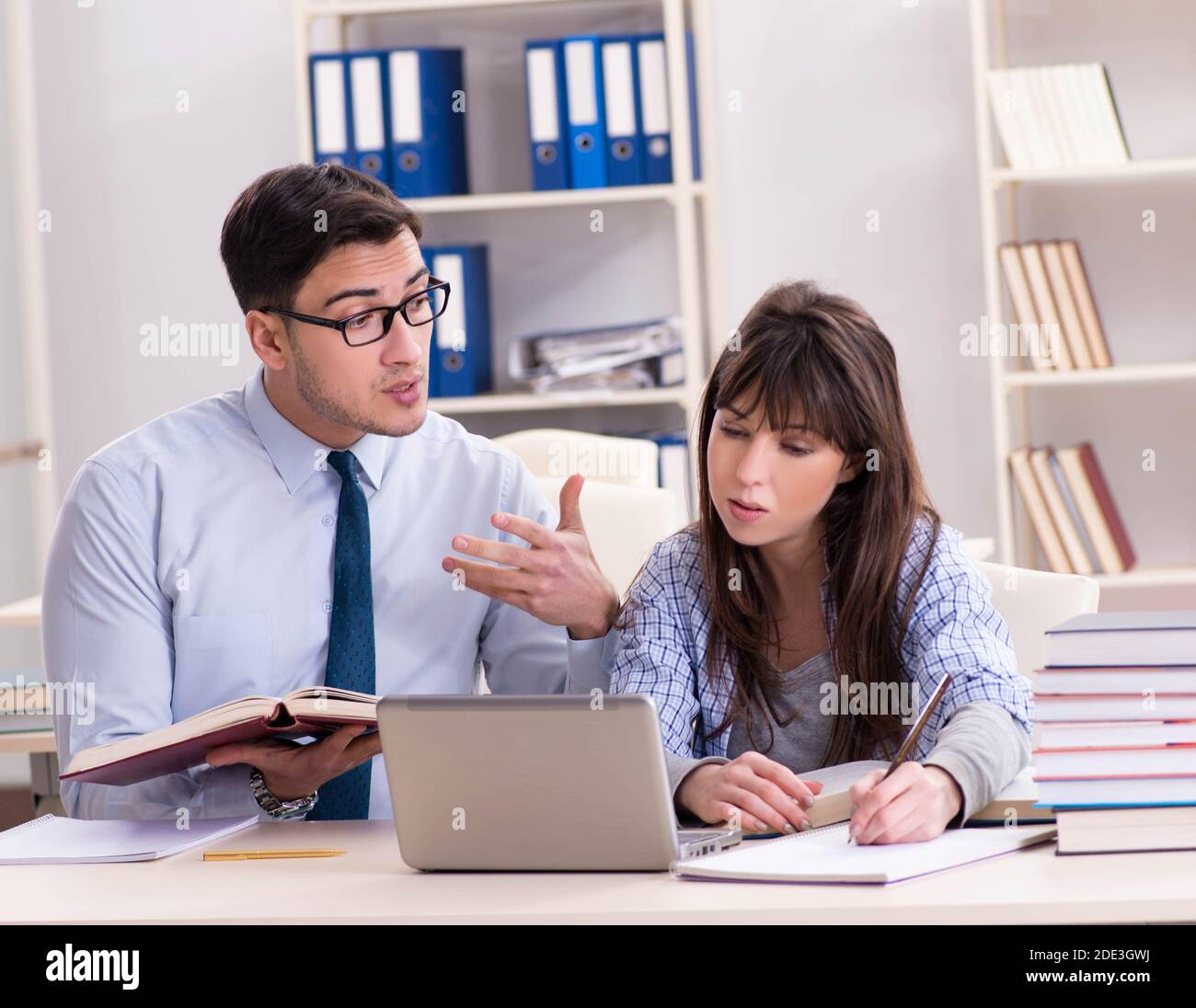 The male lecturer giving lecture to female student Stock Photo - Alamy