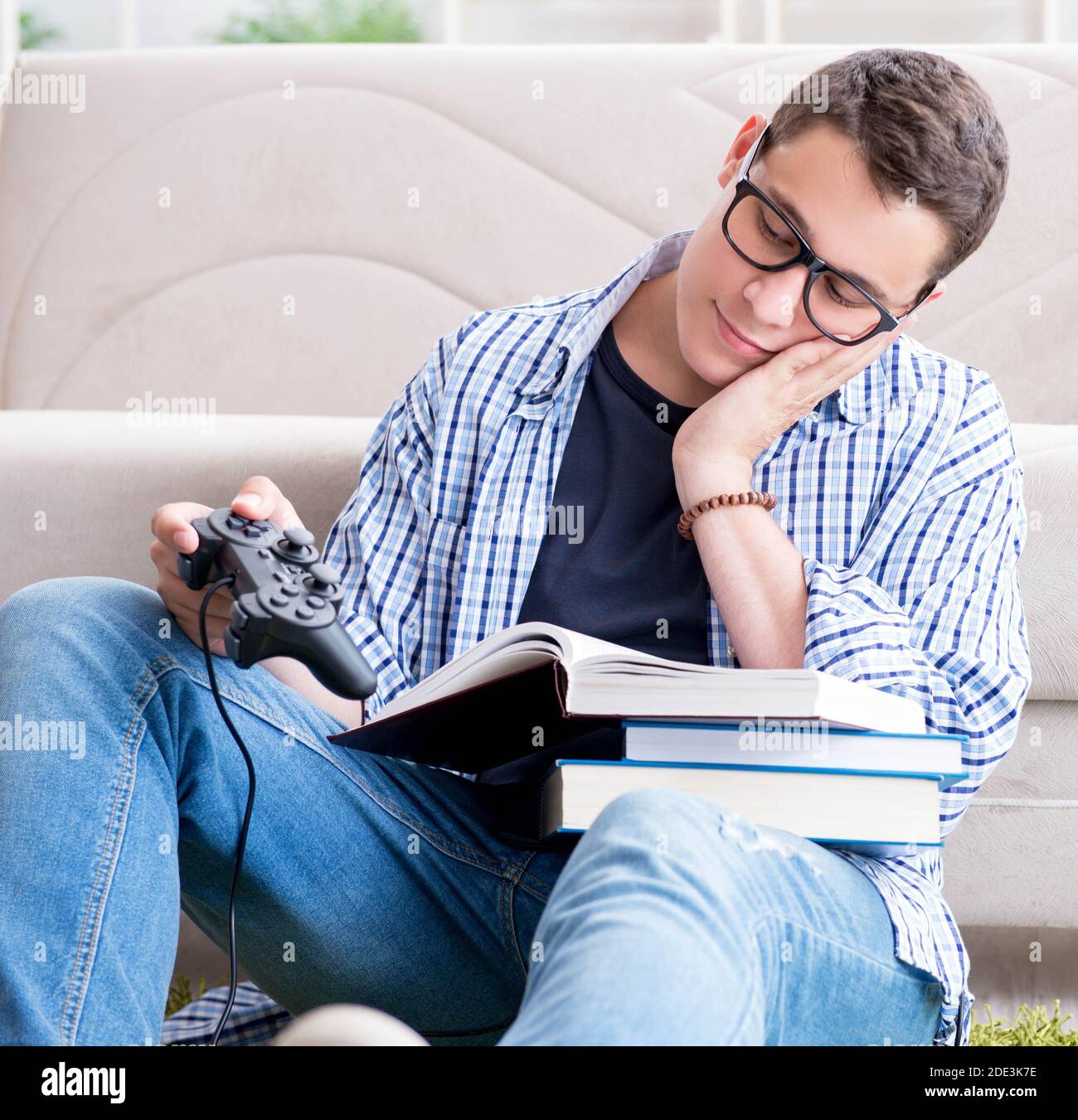 The young student trying to balance studying and playing games Stock ...