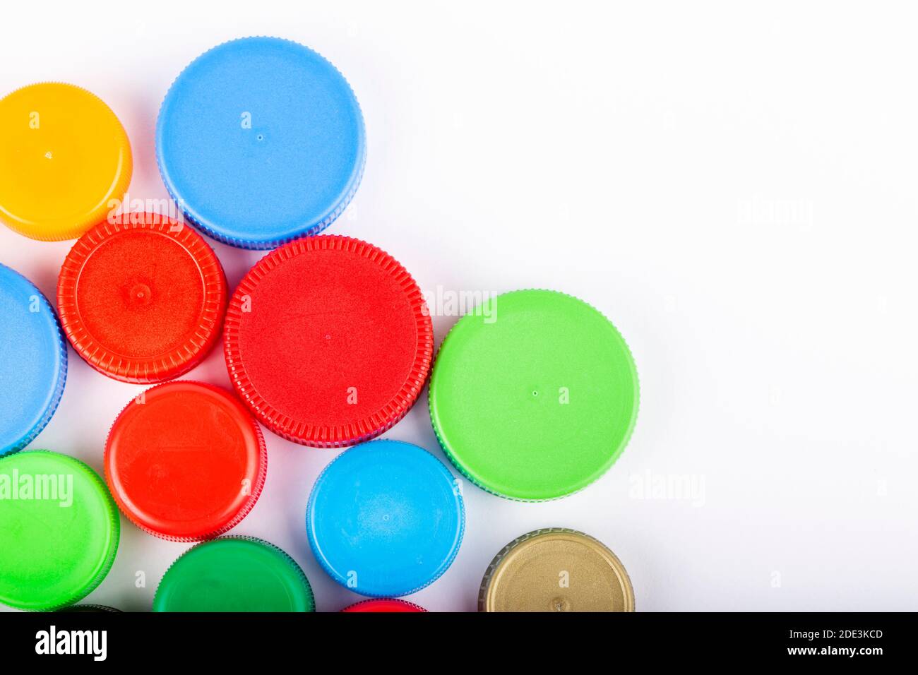 Many multi-colored plastic bottle caps on a white background. Recycling ...