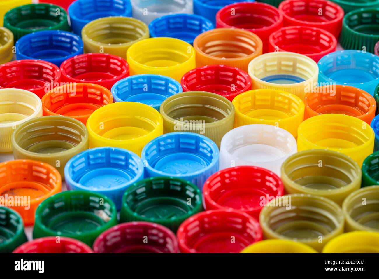 Many multi-colored plastic bottle caps on a white background. Recycling ...