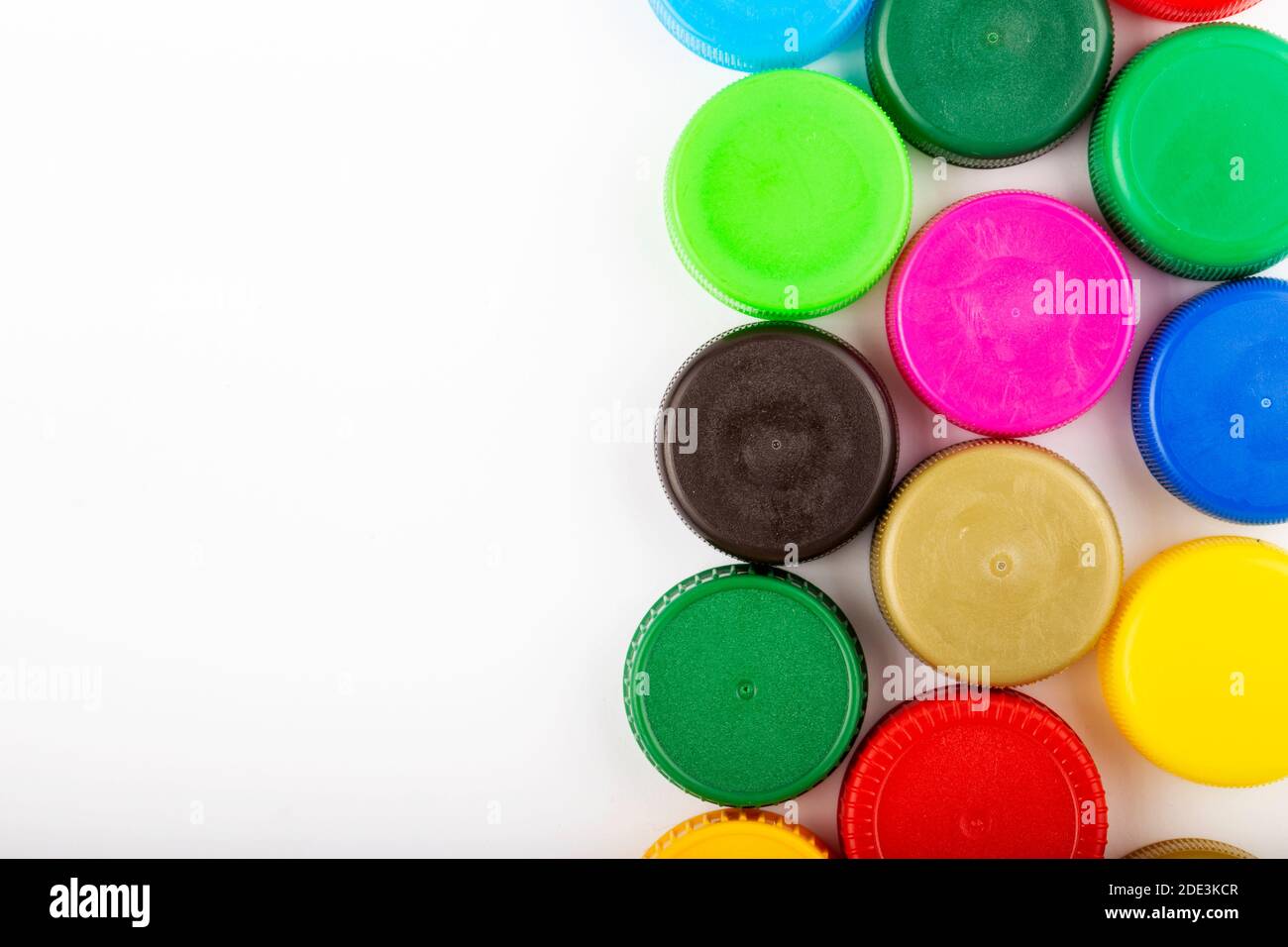 Many multi-colored plastic bottle caps on a white background. Recycling ...