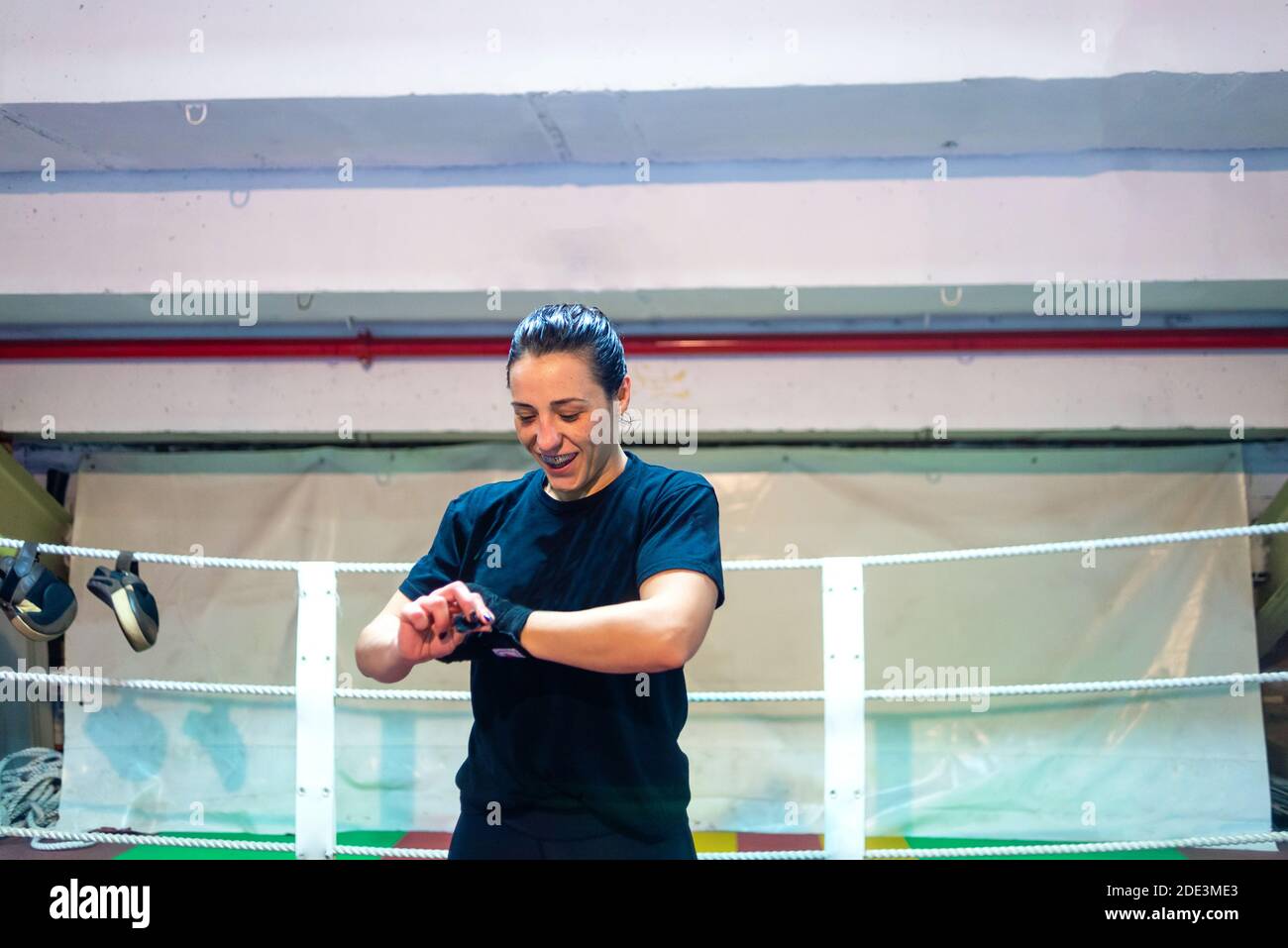 Young female boxer preparing for boxing fight,wearing strap on wrist ...