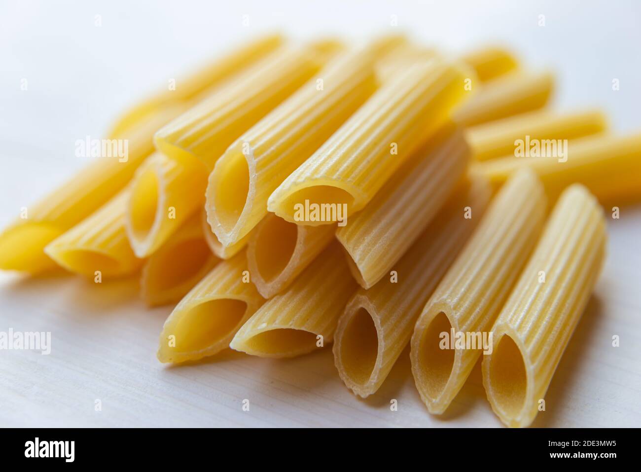 Raw penne rigate on white surface. Pasta, preparation, and price Stock ...