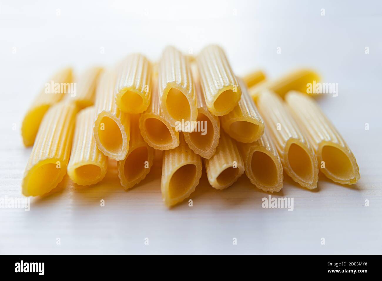 Raw penne rigate on white surface. Pasta, preparation, and price Stock ...