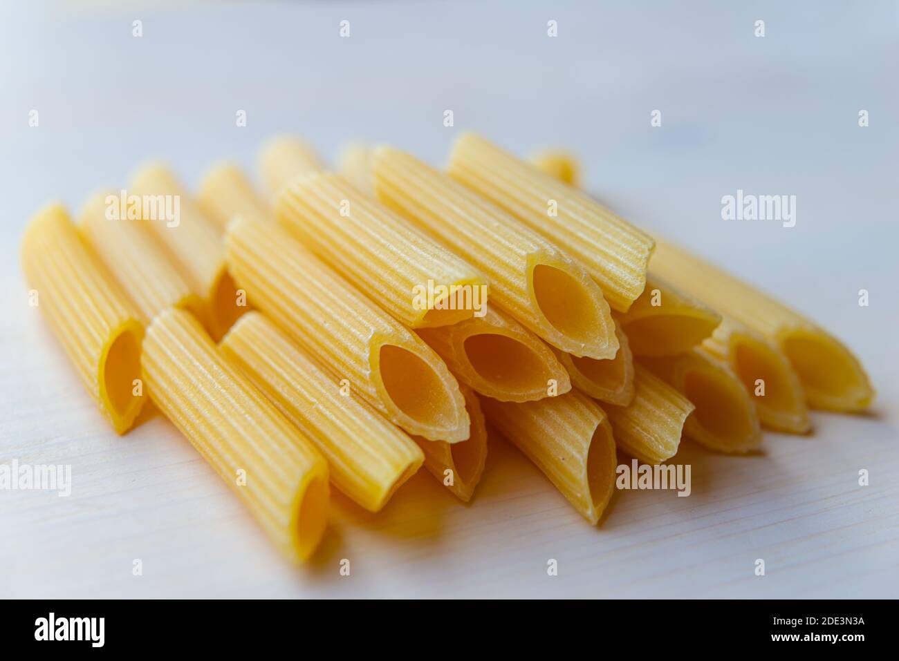 Raw penne rigate on white surface. Pasta, preparation, and price Stock ...