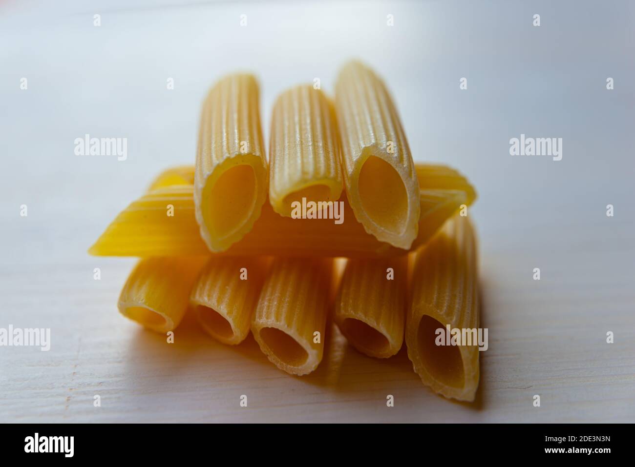 Raw penne rigate on white surface. Pasta, preparation, and price Stock ...