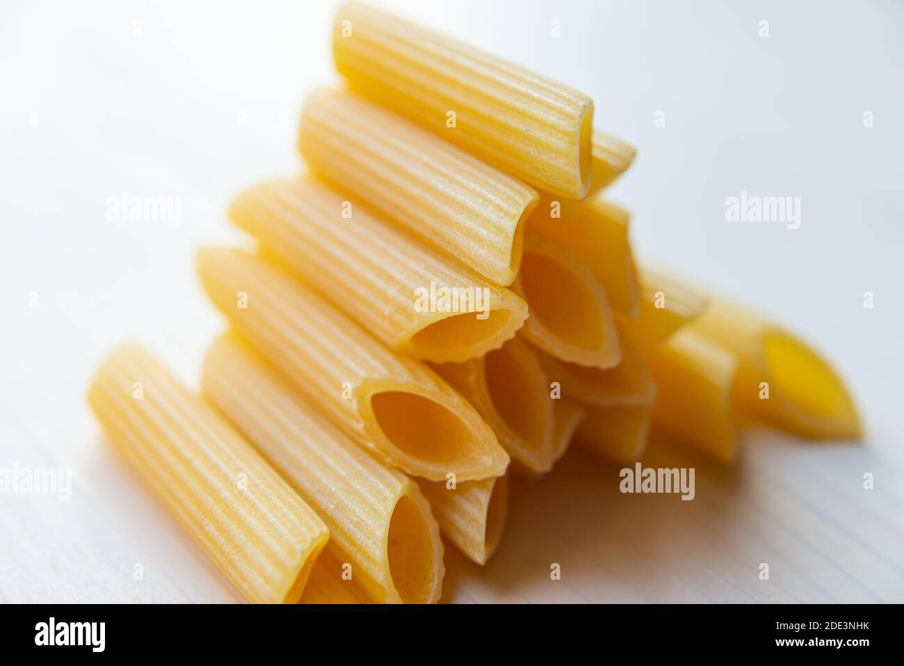 Raw penne rigate on white surface. Pasta, preparation, and price Stock ...