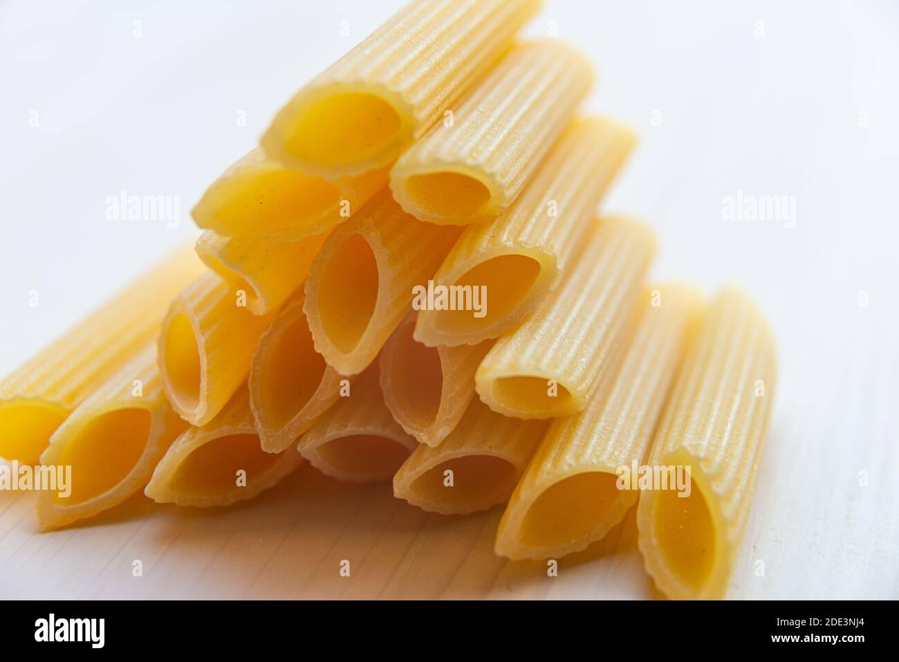 Raw penne rigate on white surface. Pasta, preparation, and price Stock ...