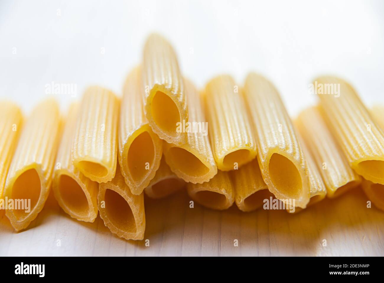 Raw penne rigate on white surface. Pasta, preparation, and price Stock ...