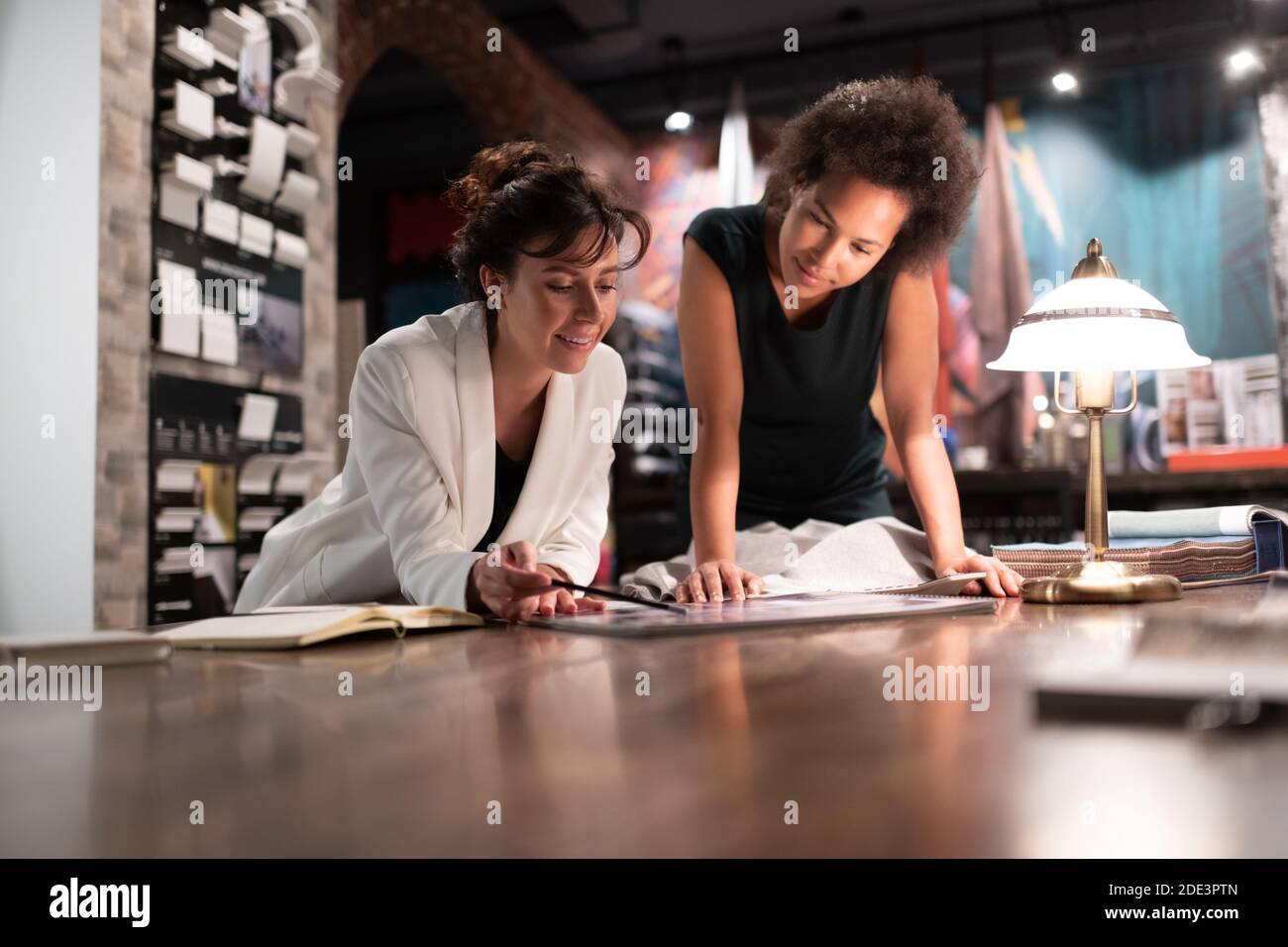 Happy female boss smiling and discussing design project with ethnic ...