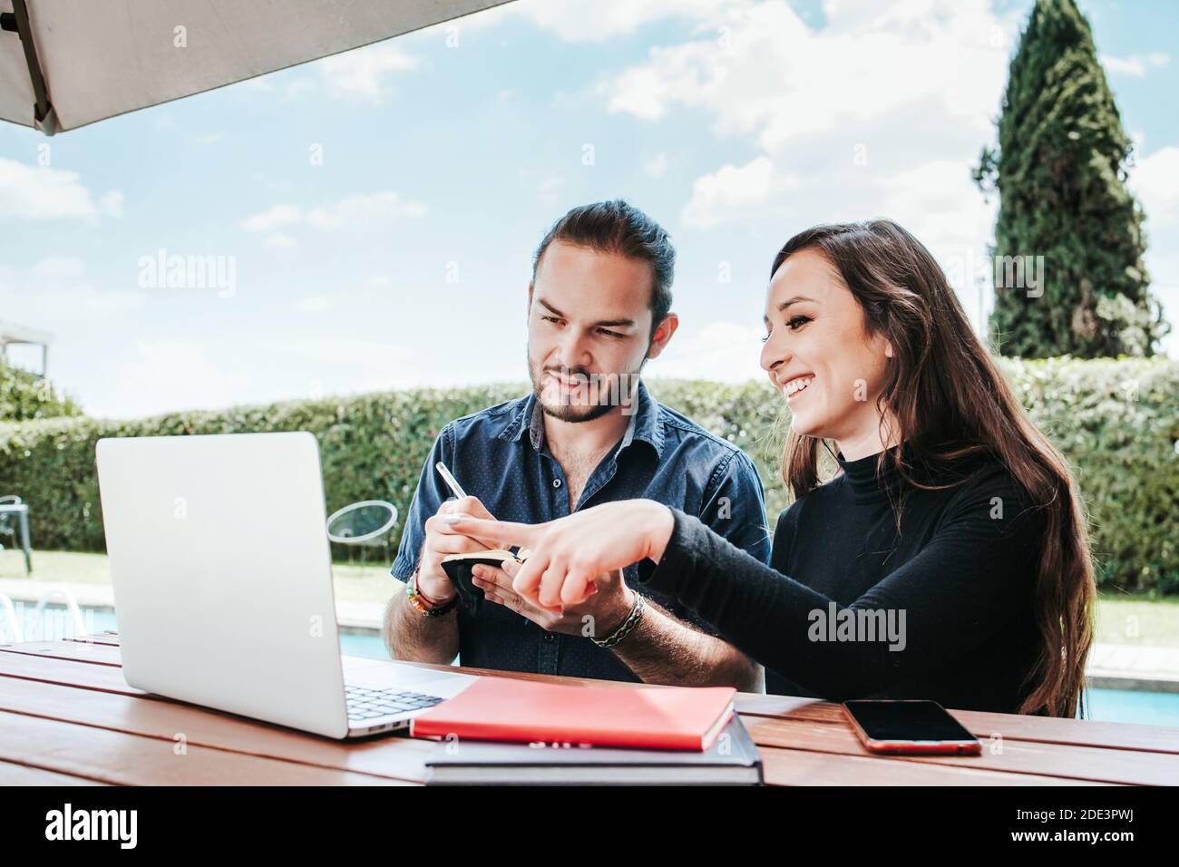 young mexican woman working on laptop while latin man sitting near her ...