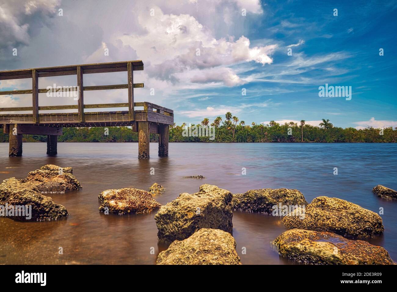 Beautiful pier scene with rocks on the shore Stock Photo - Alamy