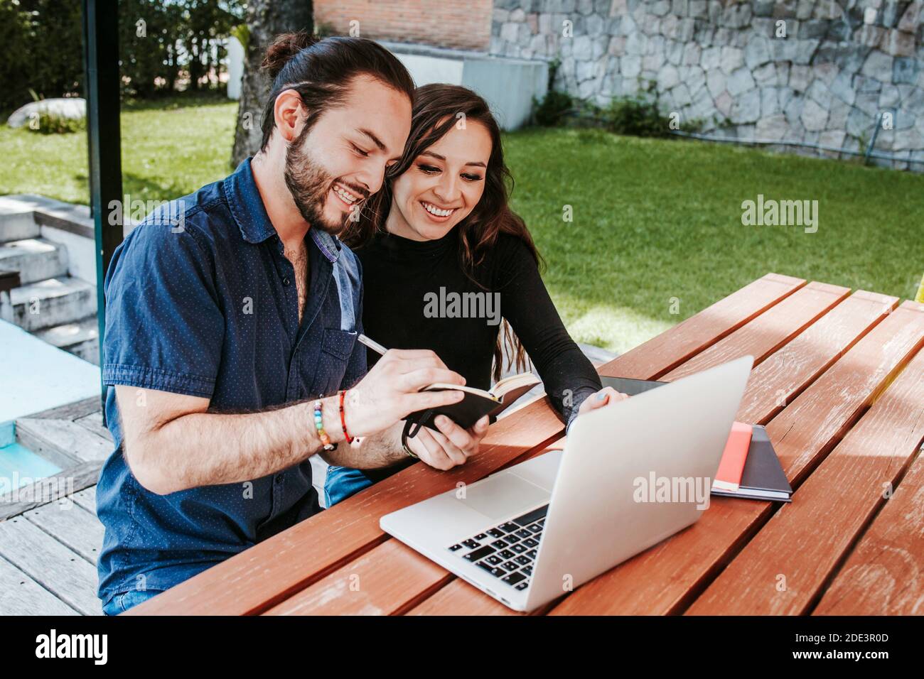young mexican woman working on laptop while latin man sitting near her ...