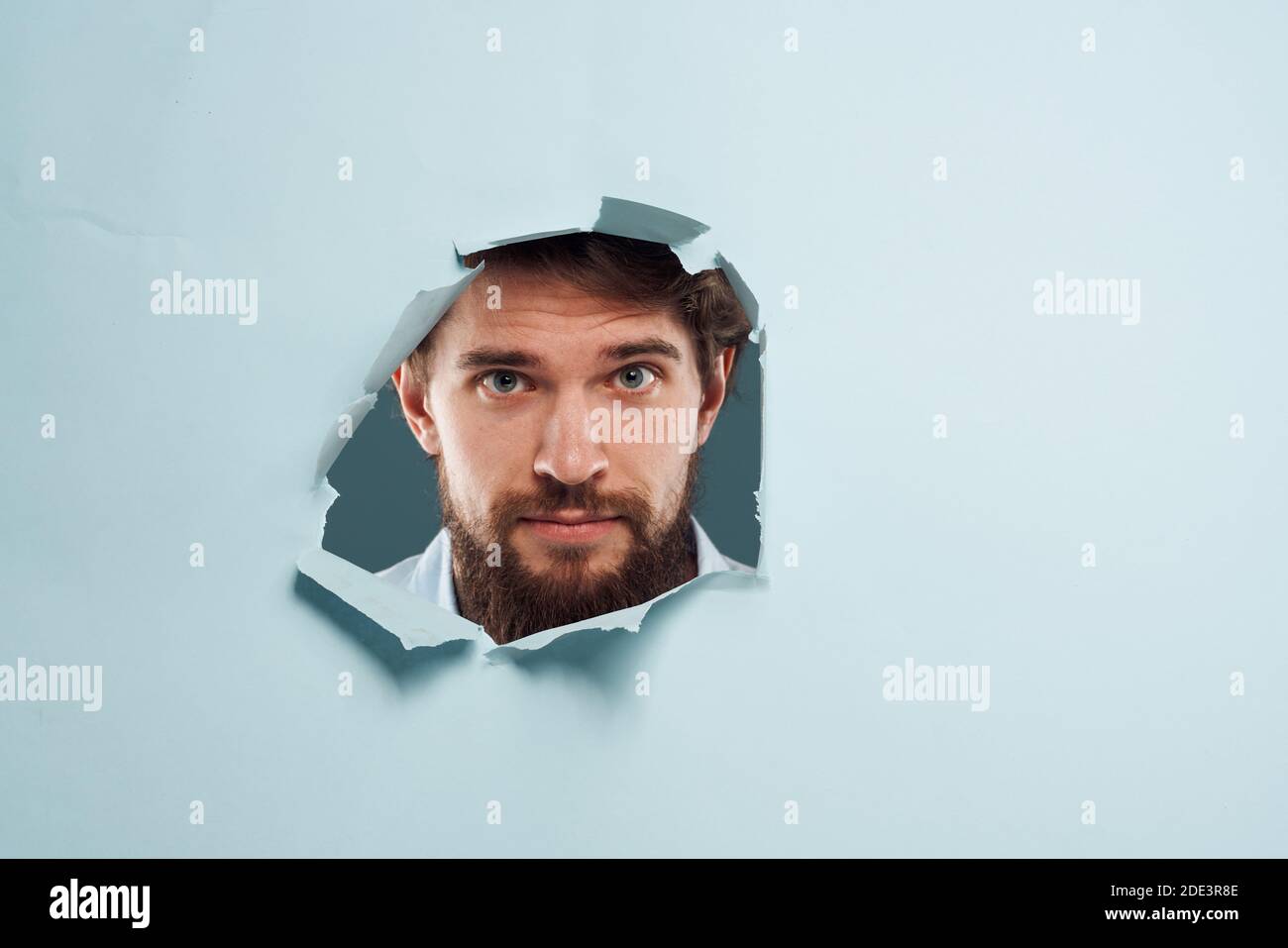 Emotional man peeps his head out of the blue background wall Stock ...