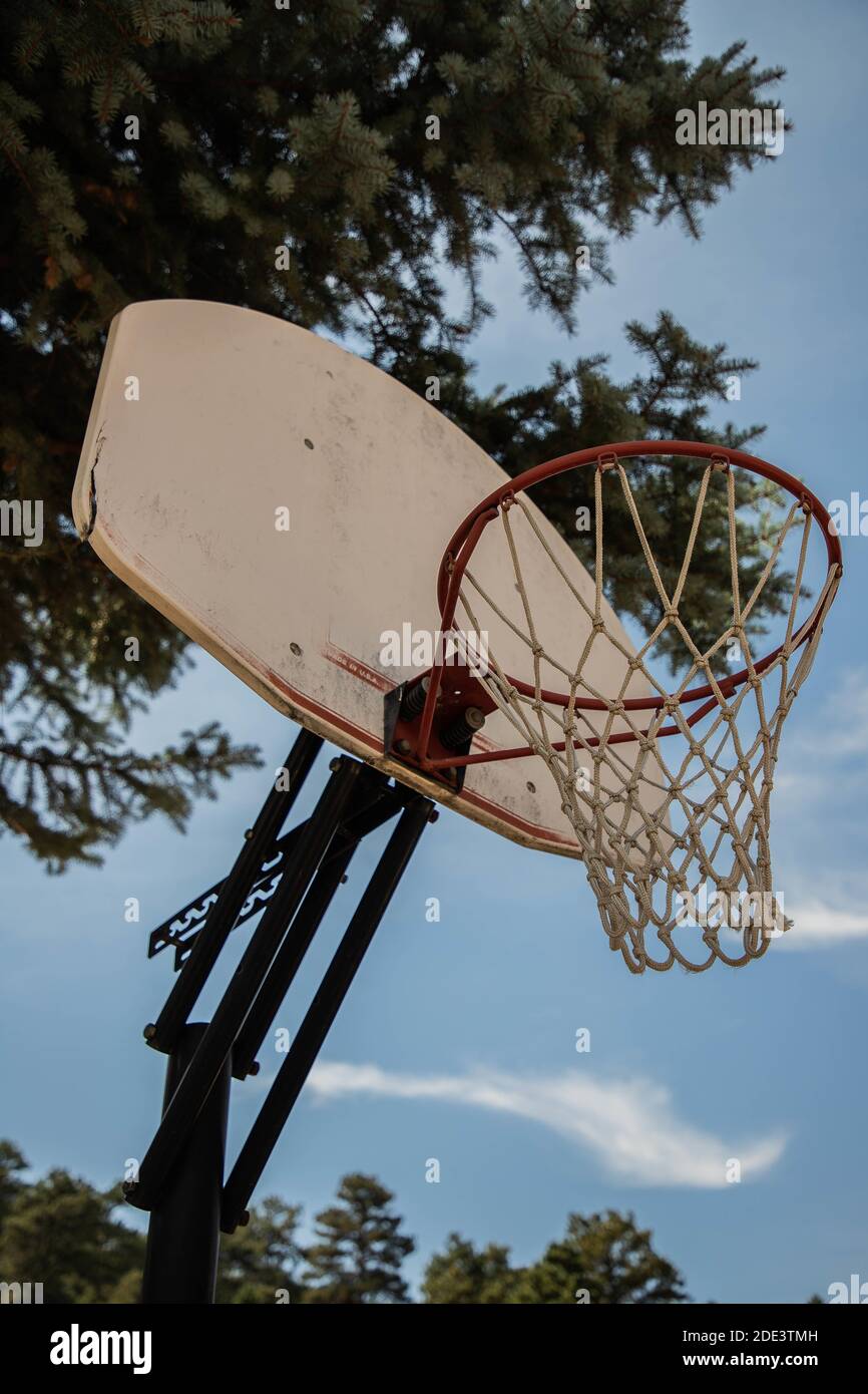 A vertical shot of a basketball net in a playground under a blue sky ...