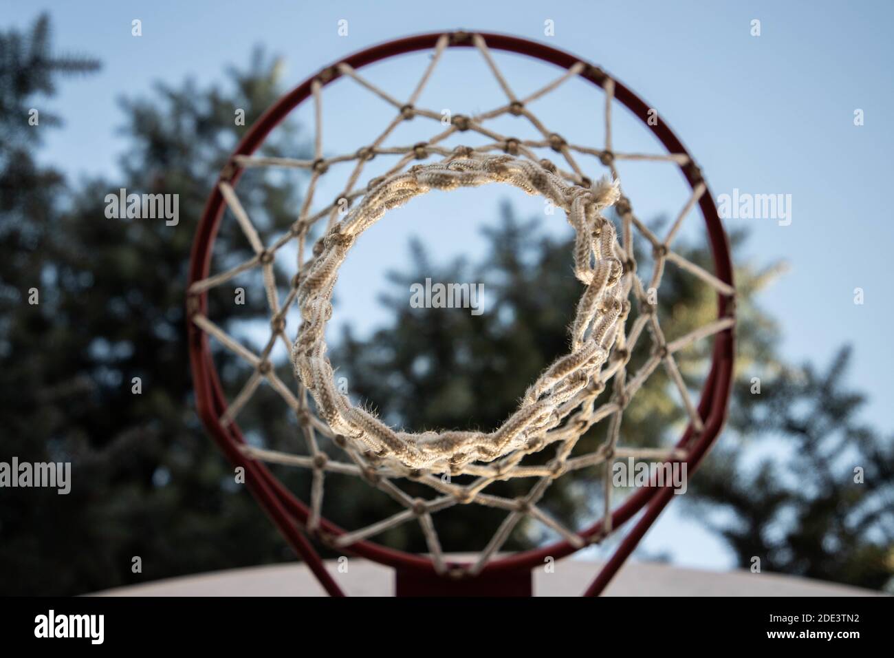 A low angle shot of a basketball net in a playground under a blue sky ...
