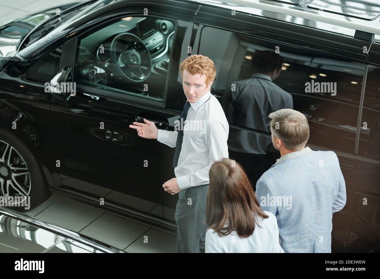 Young sales manager showing new model of car and describing its ...