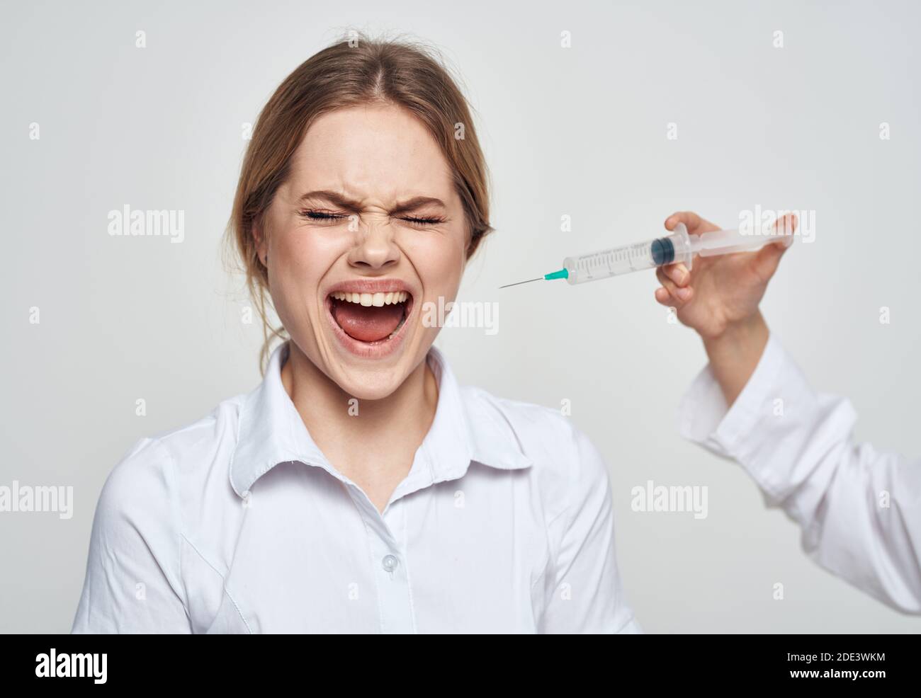 Syringe with liquid and a female patient in a white t-shirt health ...
