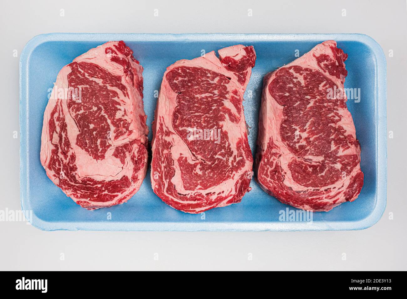 Three Freshly Cut Prime Grade Boneless Ribeye Steaks Being Packaged On A Butcher Table Stock