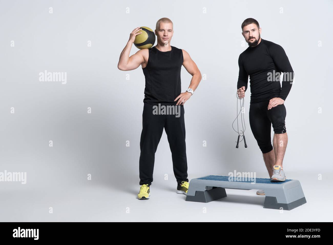 two athletic personal fitness trainers or bodybuilders on white ...